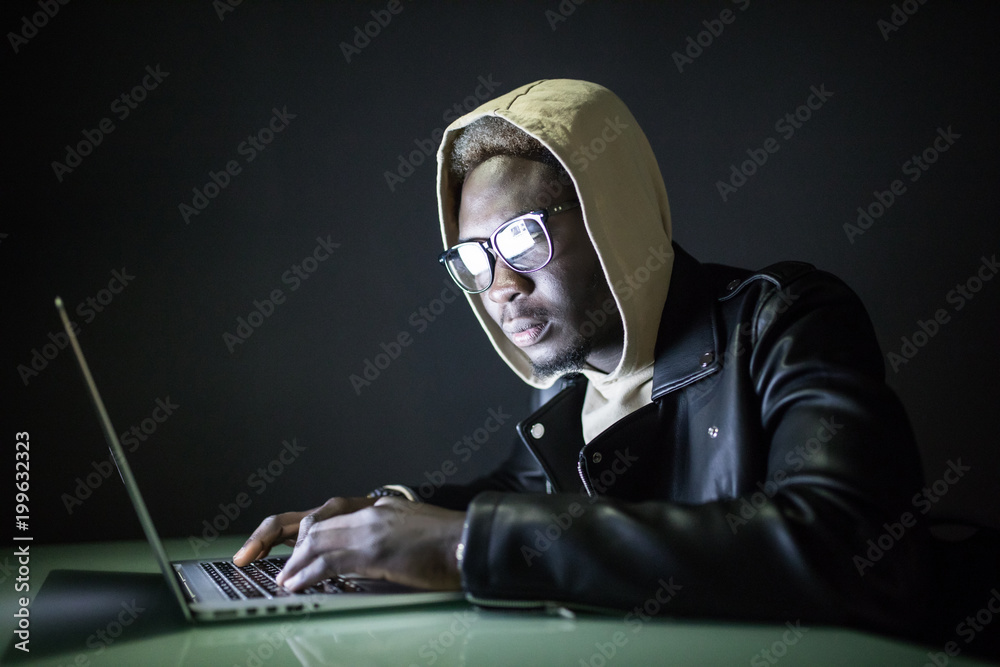 Serious young afro american man using blank screen computer in the dark ...