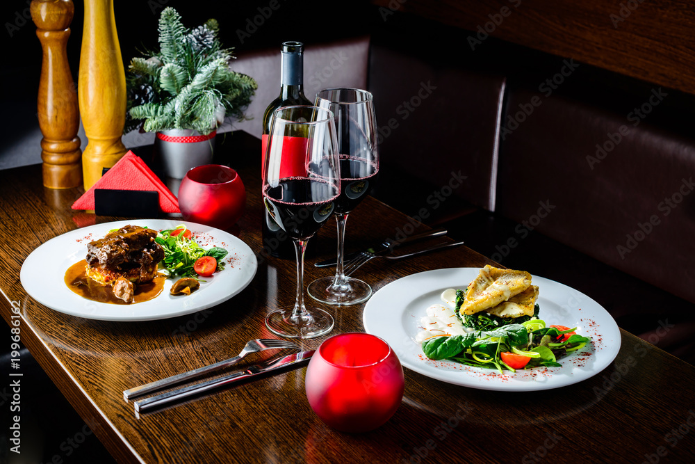Romantic dinner in a restaurant. Tasty dishes and glasses of wine on a ...