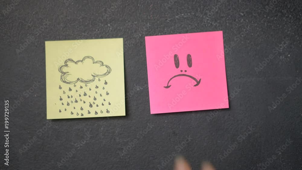 Closeup woman's hand sticking note with sad face icon next to the rainy ...