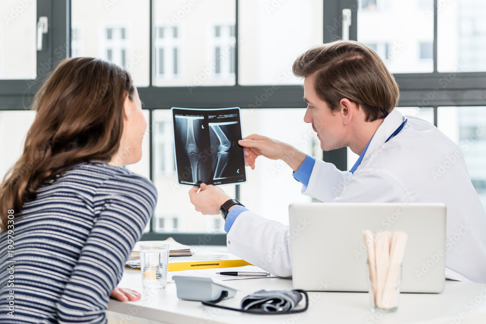 Experienced orthopedist analyzing and interpreting to his female ...