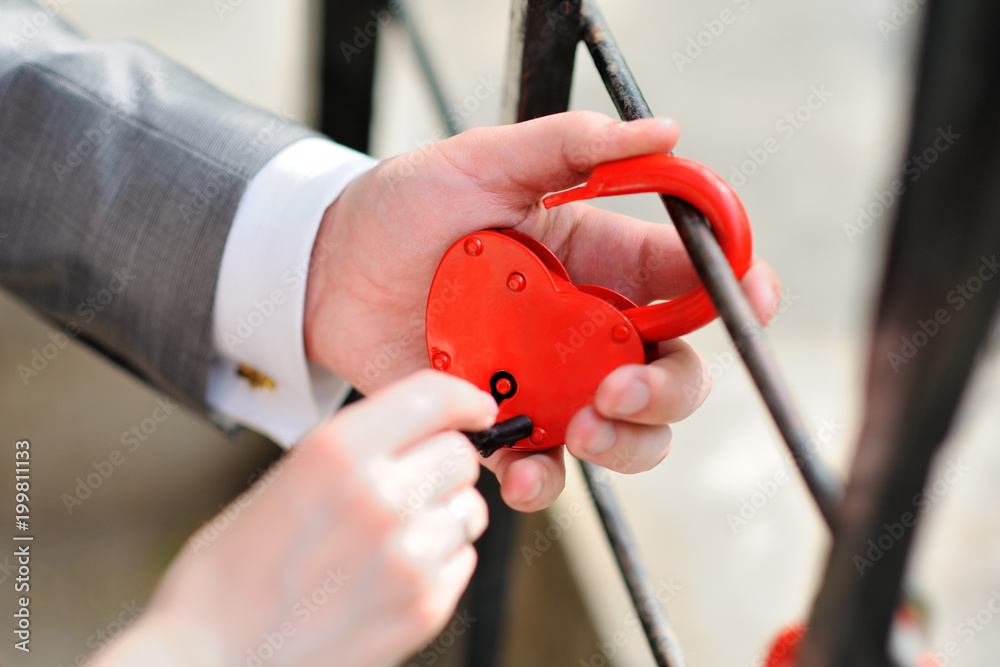 Red lock in the form of a heart. Newlyweds hang the lock symbolizing ...