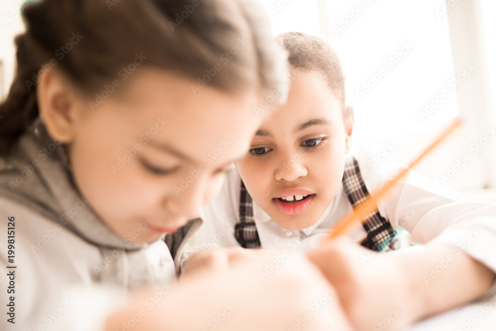 Little girl helping her friend during a lesson at school Stock Photo ...
