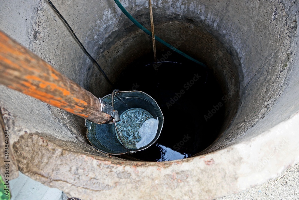 iron bucket with water at the depth of a round well Stock Photo | Adobe ...