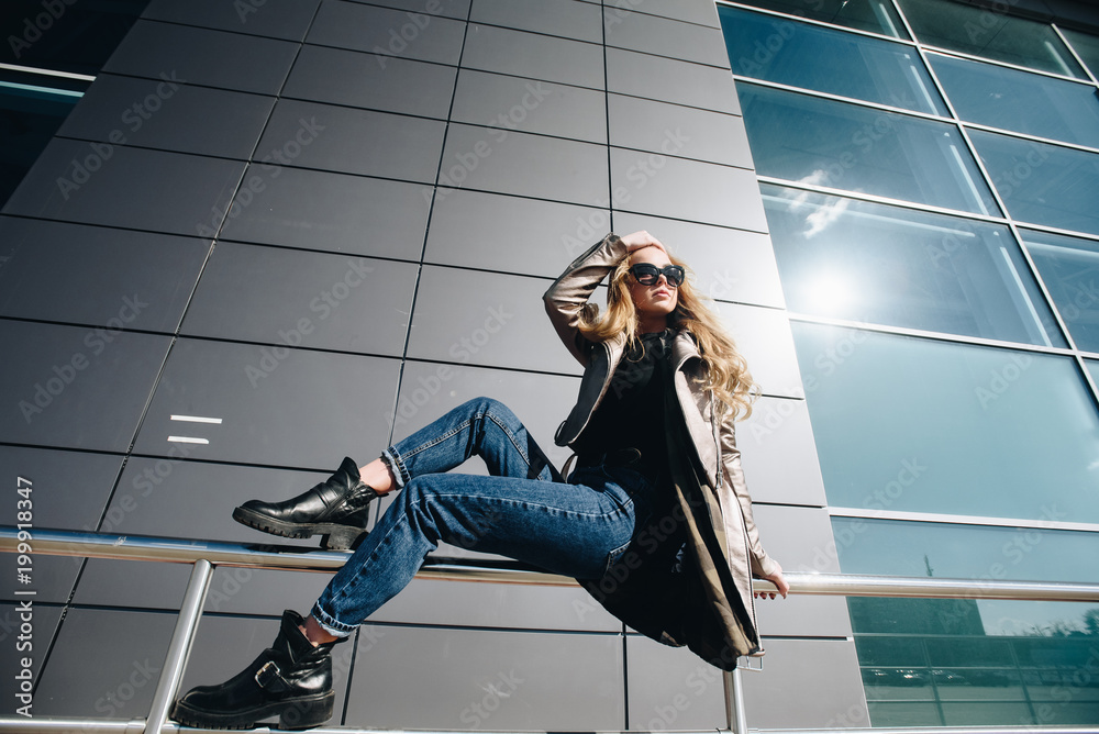 Fashion style. A model in a jacket and jeans poses on the street. City ...