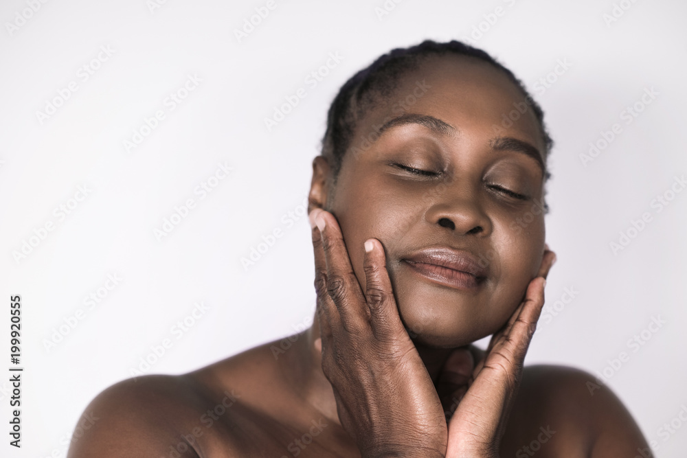 Mature African woman touching her cheeks against a white background ...