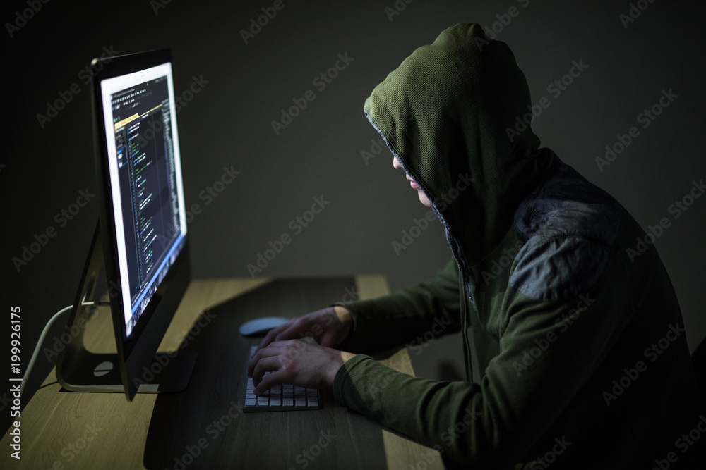 Computer hacker in hood working in dark room code on pc and hack ...