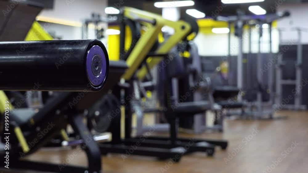 The interior of an empty gym - blurred - an end of an unloaded barbell ...