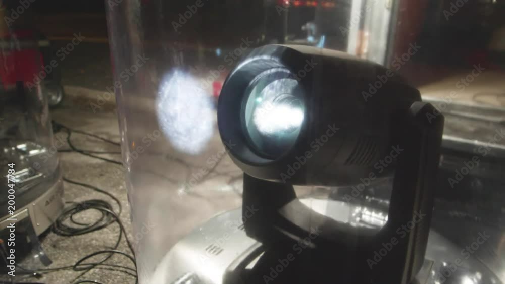 Camera tracks and pans around a projection light and into the beam of ...