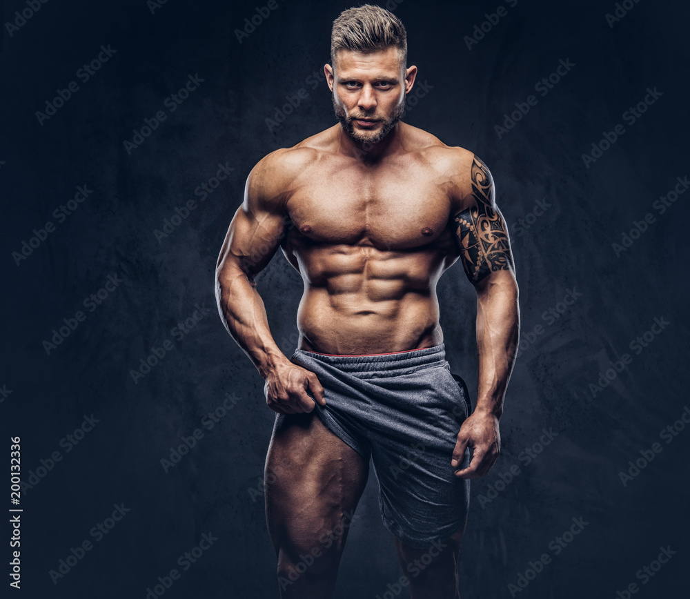 A handsome shirtless tattooed bodybuilder with stylish haircut and ...