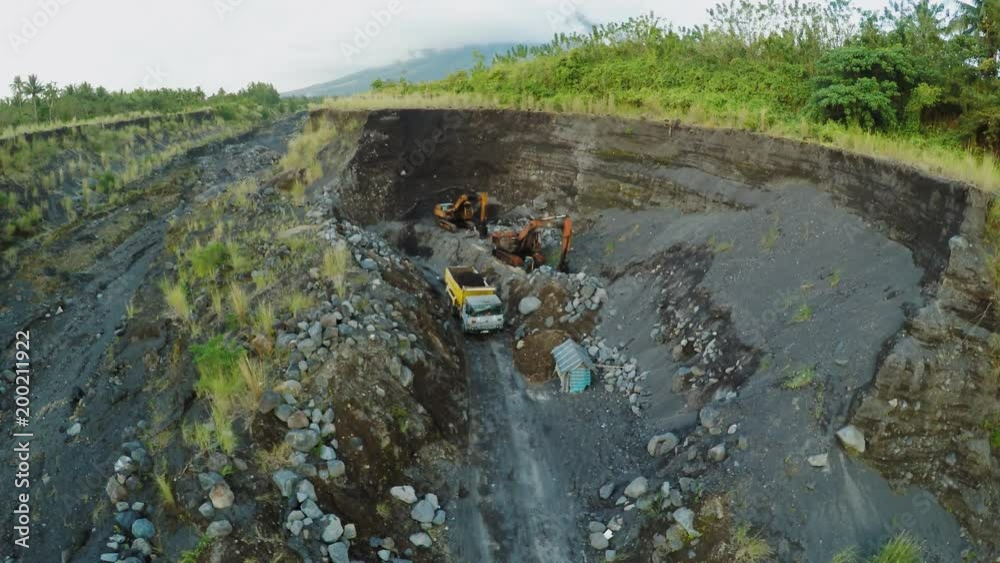 Excavator and truck take volcanic ash from the outflowing river ...