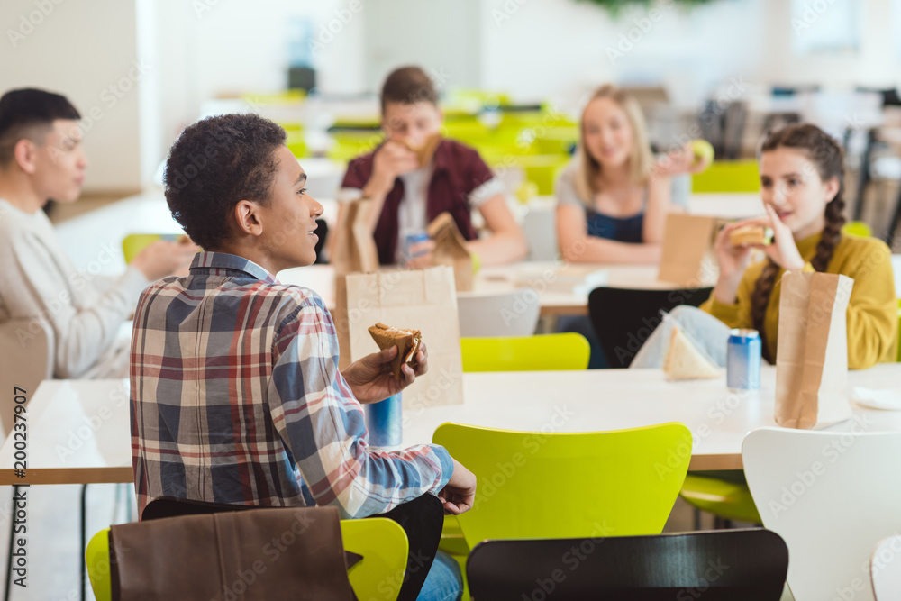 group of high school students chatting while taking lunch at school ...