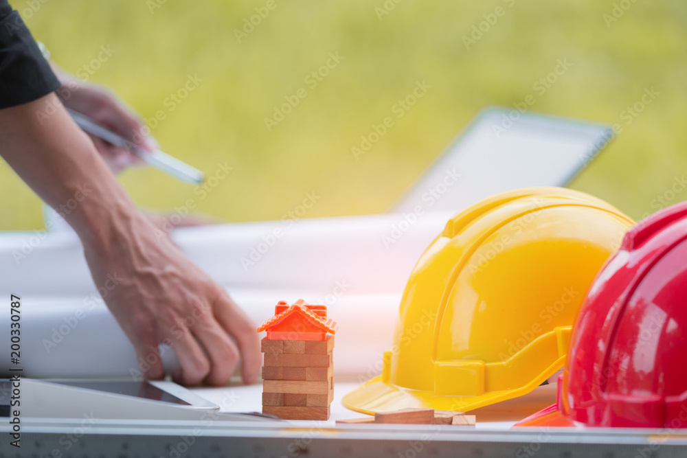 Engineer hard helment with house model and orange roof, working with ...