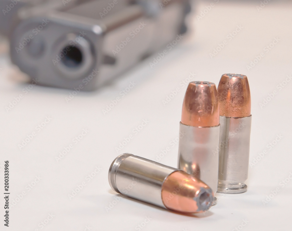 Three 9mm hollow point bullets on a white table in front of a black pistol Stock Photo | Adobe Stock