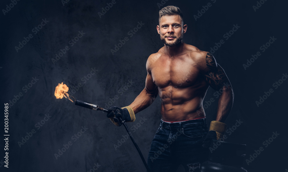 Brutal tattoed male welder with a stylish haircut and beard, with ...