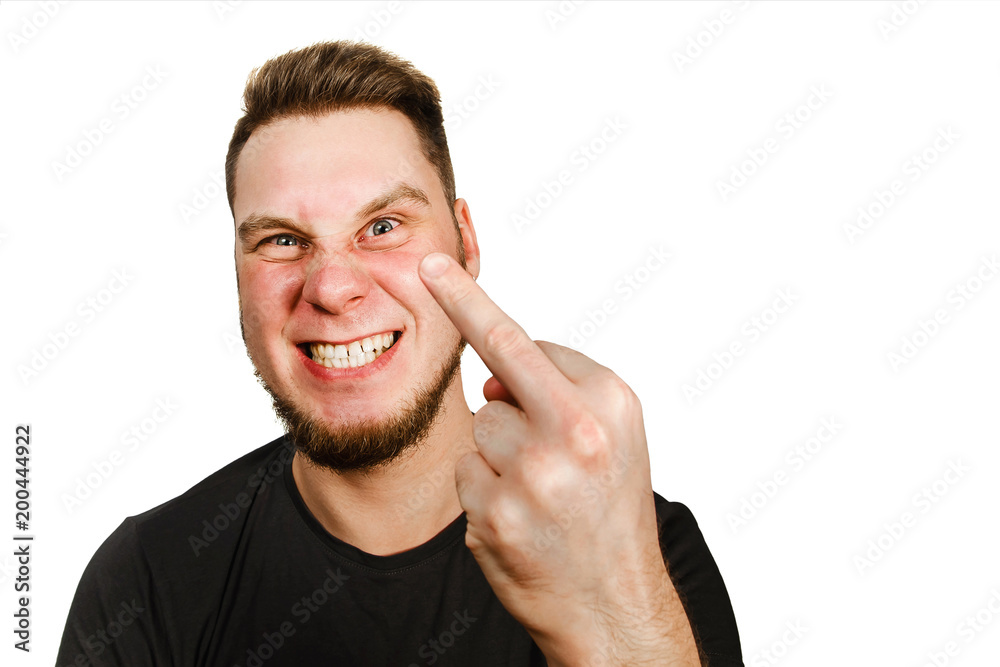 Young smiling guy with beard and modern hairstyle shows middle finger ...