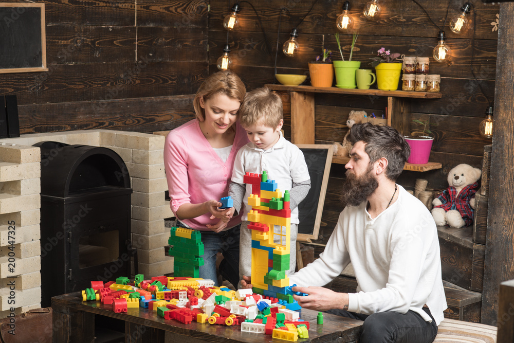 Mom, dad and kid sitting around table with colorful construction bricks ...