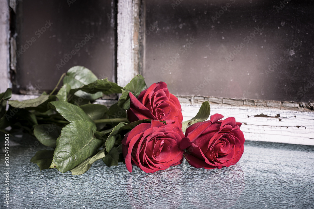 Three red roses on a texture glass. Against the background of the ...
