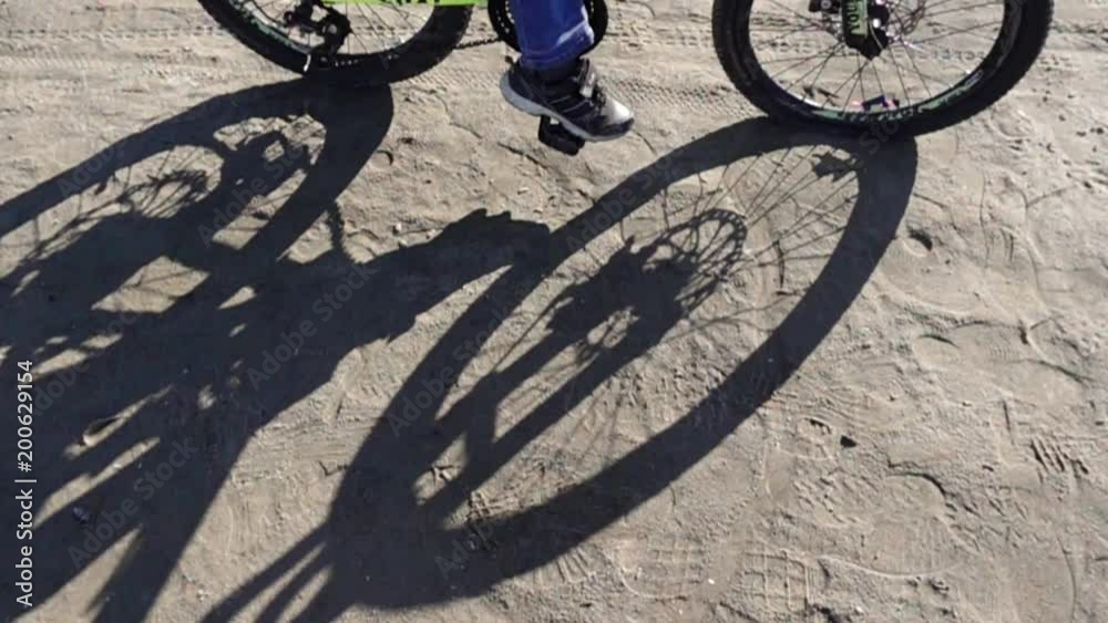 The child is riding a bicycle. In the frame, the movement of the shadow ...