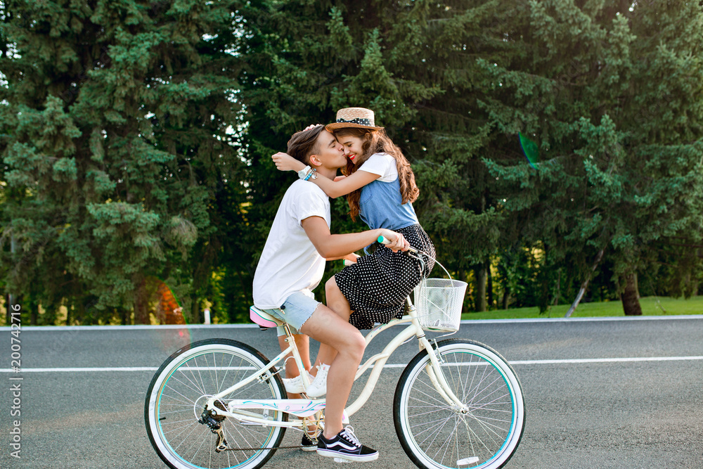 Full-length photo of young couple in love on bike on road on forest ...