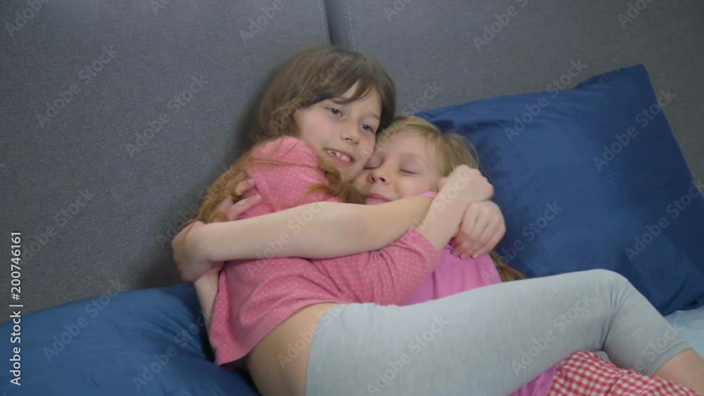 funny sisters fooling around on bed. two girls hugging and clinch each ...