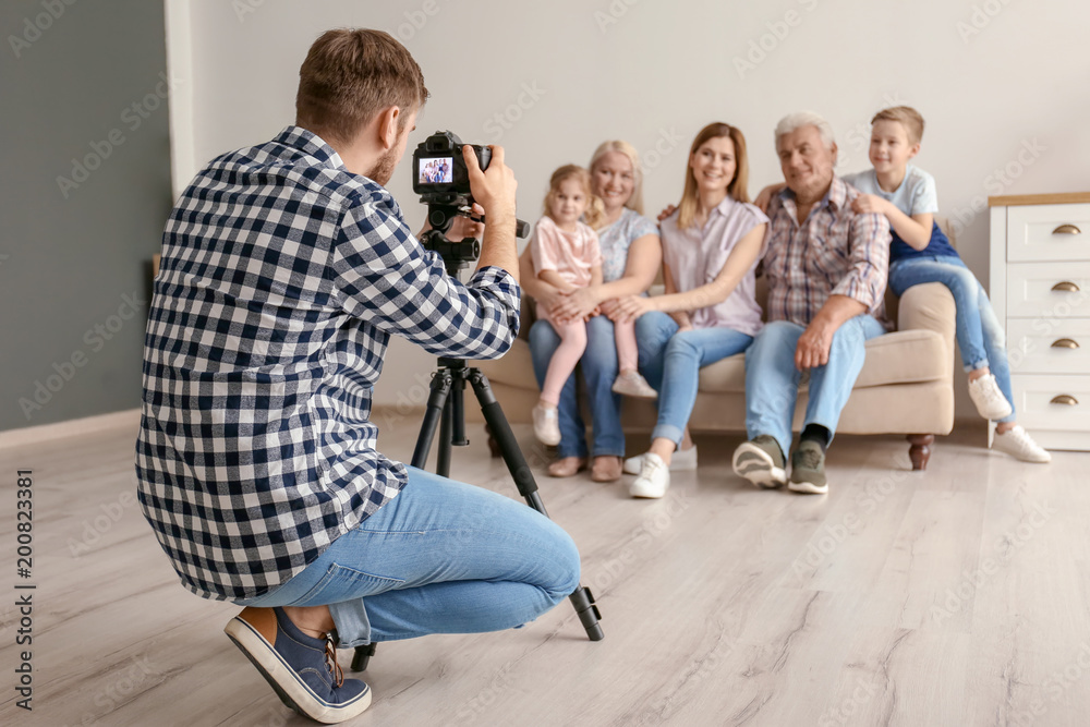 Professional photographer taking photo of family on sofa in studio ...