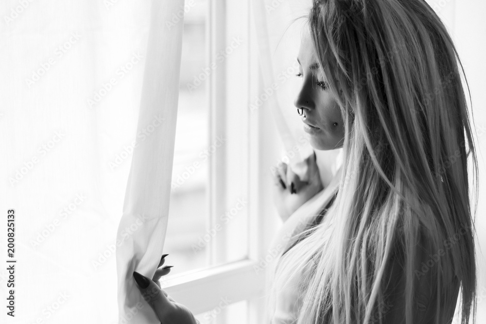 Modern and beautiful woman standing in front of the window. In her ...