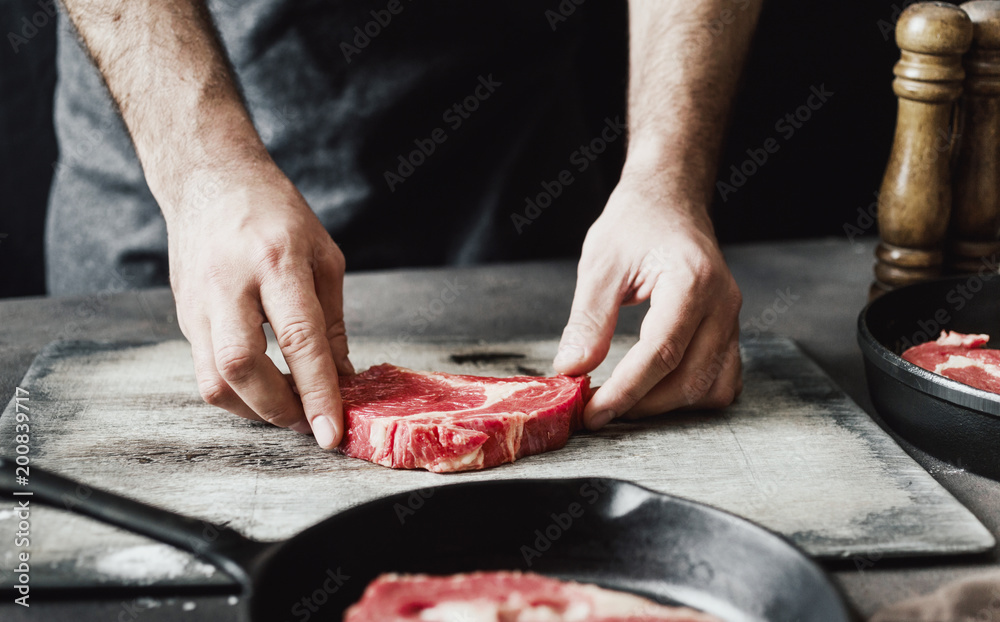 Man preparing beef steak on wooden table Stock Photo | Adobe Stock