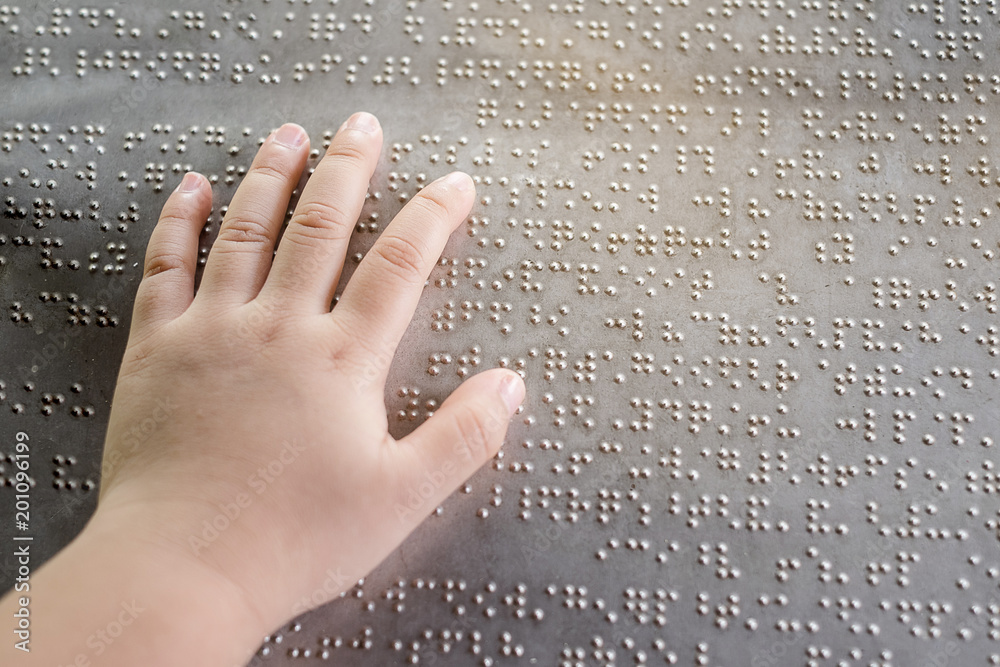 The blind kid's hand and fingers touching the Braille letters on the ...