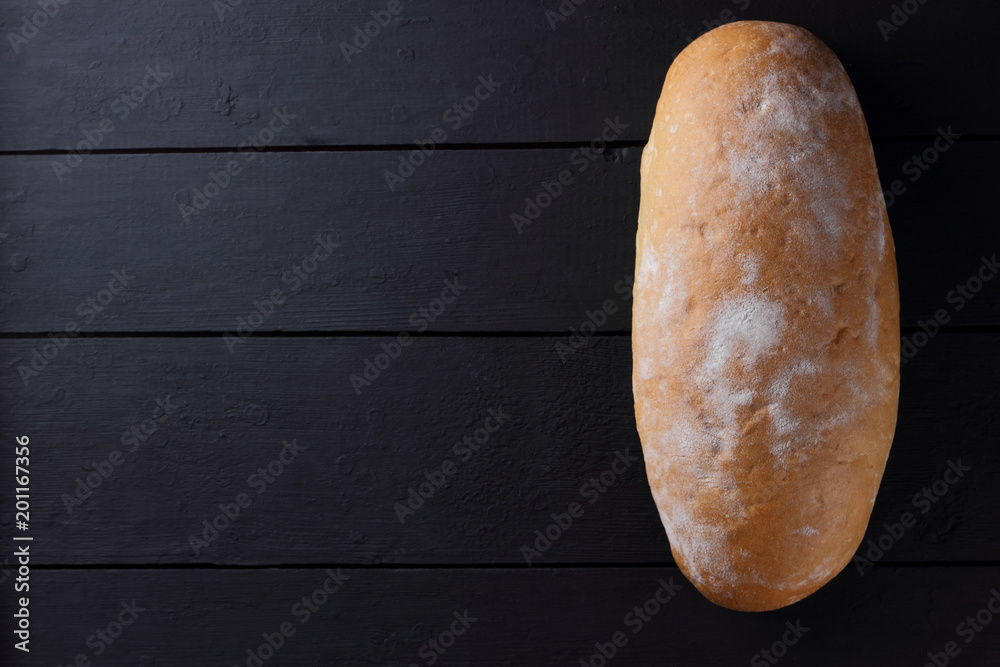 Round bread on a black background, bread from a stove on dark boards ...