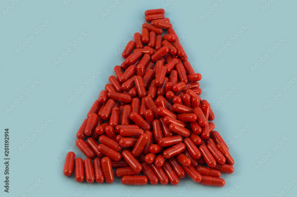 Medical capsules of red color, laid in the shape of an isosceles ...