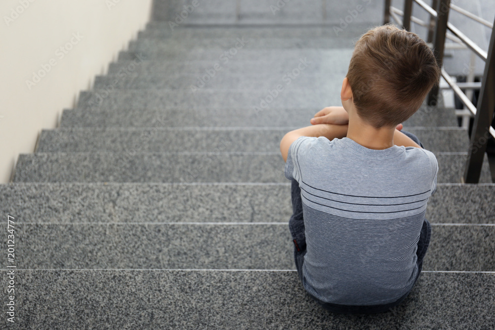 Lonely little boy sitting on stairs. Autism concept Stock Photo | Adobe ...