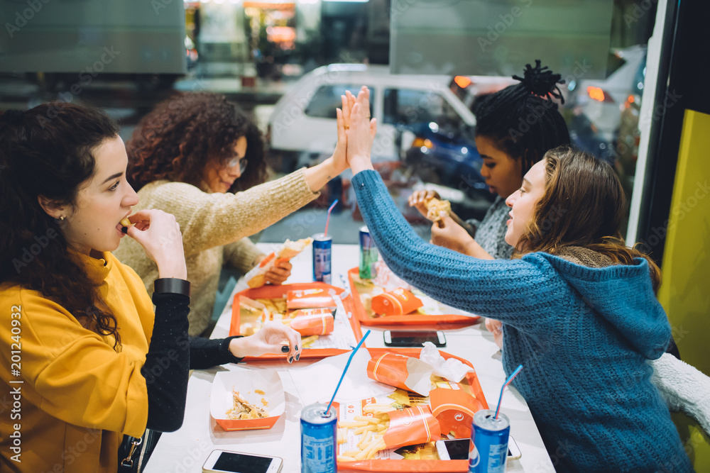 four young women multiethnic indoor eating at fast food - food and ...