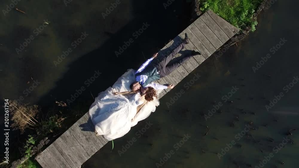 Brides are lying on a small bridge in the park. Aerial view on top ...