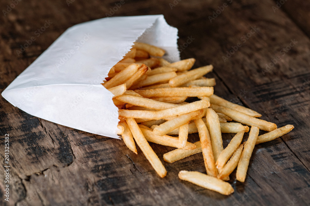 French fries potatoes in a paper bag on wood background Stock Photo ...