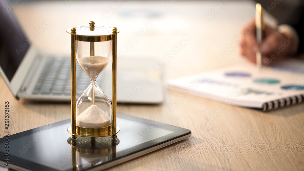 Time is running in hourglass, female manager checking graphs at office ...