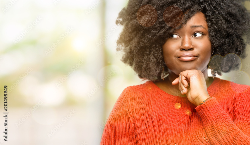 Beautiful african woman thinking and looking up expressing doubt and ...