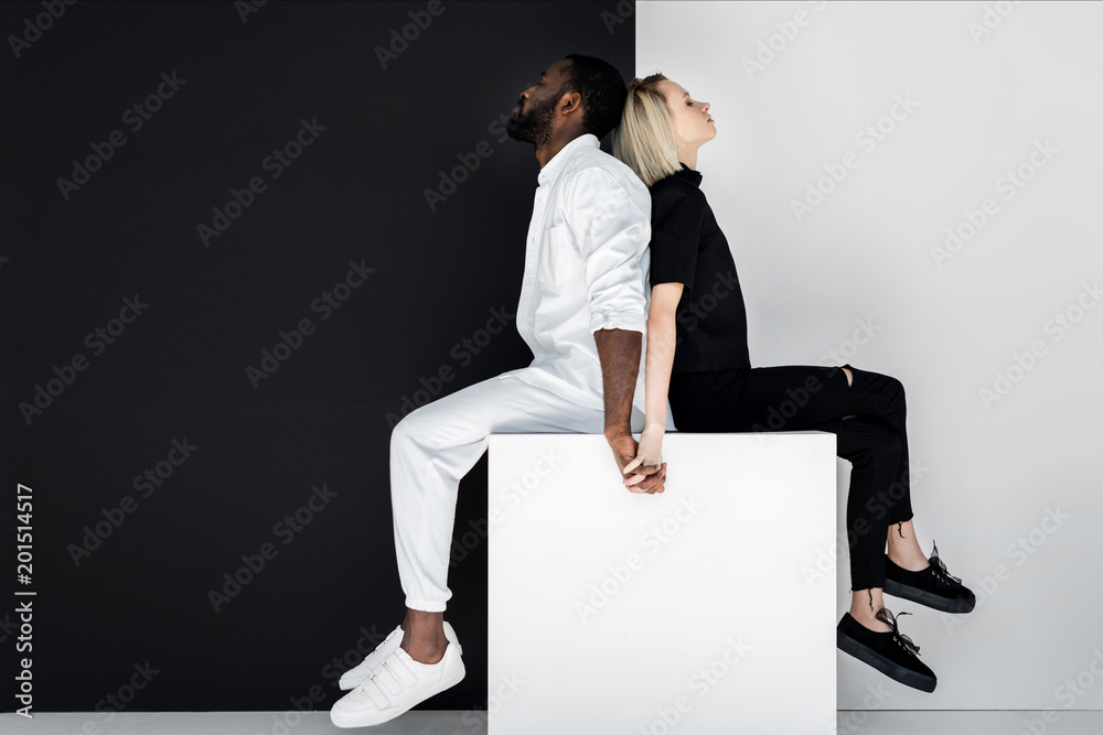 multicultural couple holding hands on white cube, yin yang concept ...
