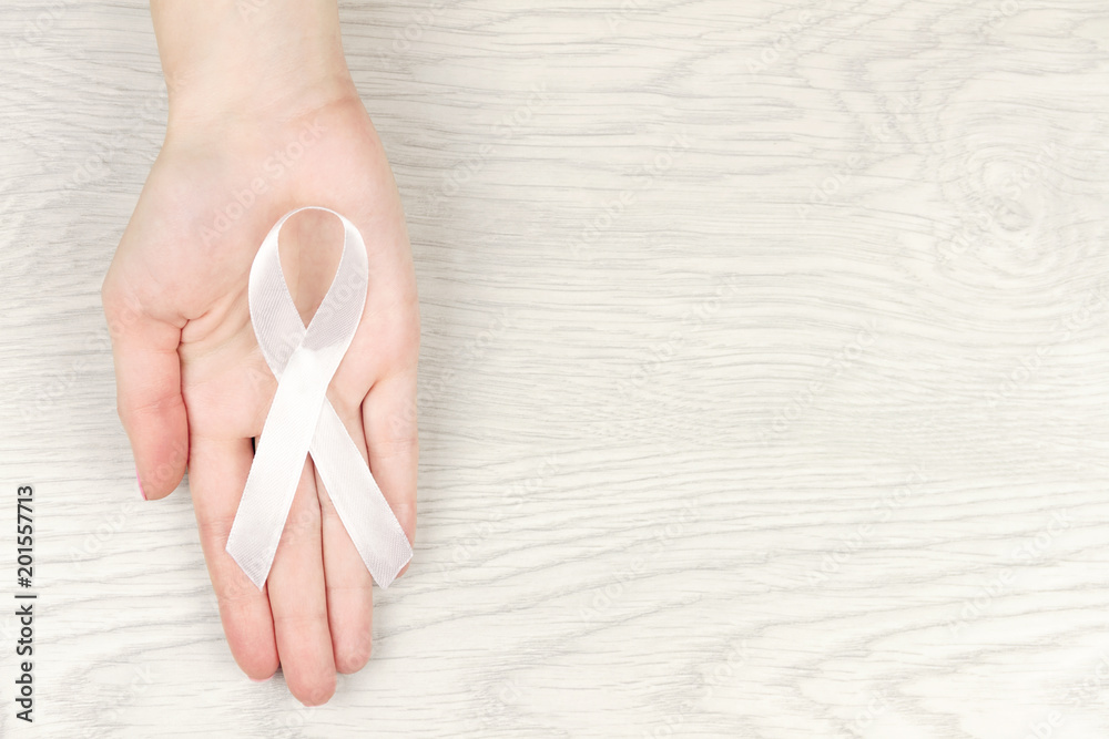 Oncological disease concept. Hand holding white ribbon as a symbol of ...
