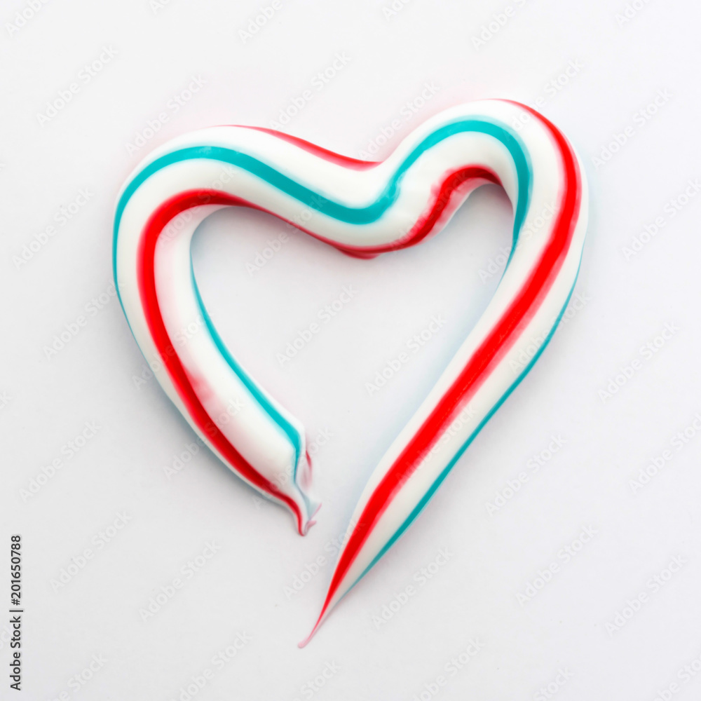 heart symbol is made of three-color toothpaste on white background ...