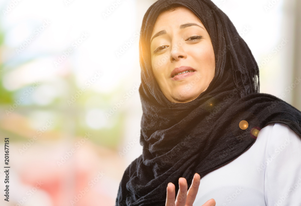 Young arab woman wearing hijab disgusted and angry, keeping hands in ...