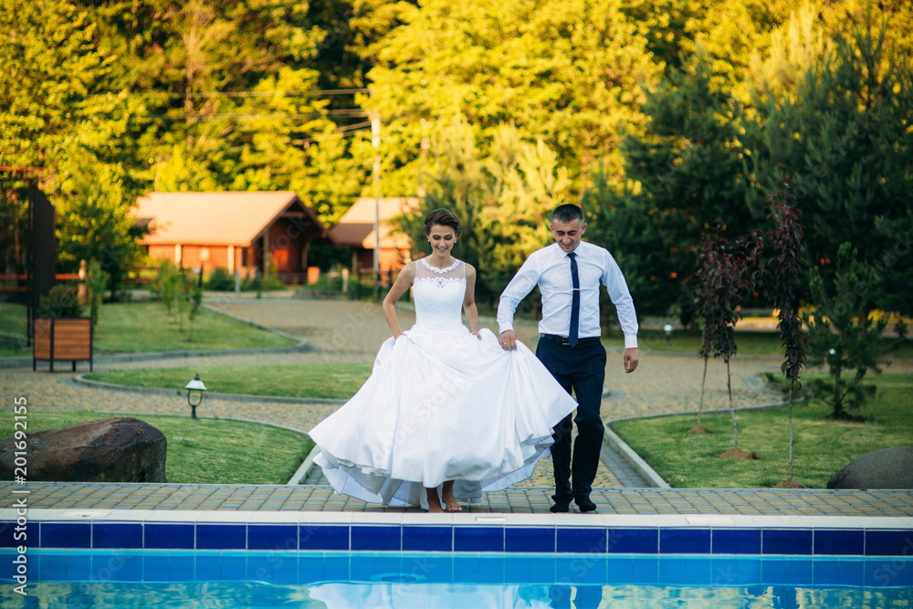 Young couple jumping in the swimming pool in a wedding suit and wedding ...
