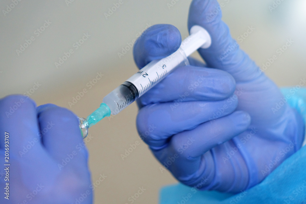 The nurse draws the solution into the syringe from the bottle in the ...
