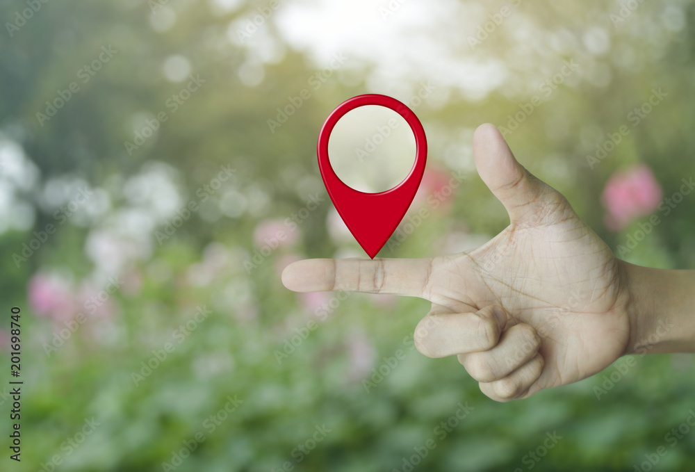 Map pin location button on finger over blur pink flower and tree, Map ...