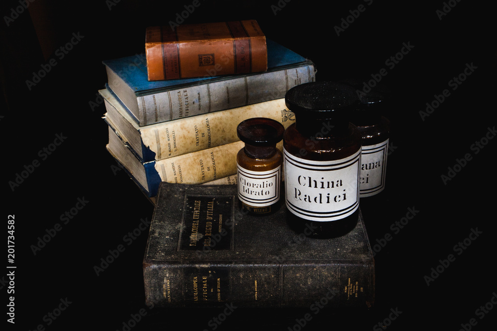Old books (Italian Pharmacopeia and Pharmacology books) and old glass ...