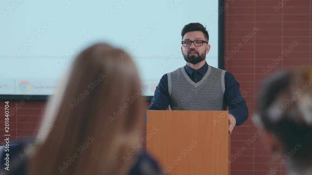Young university professor is standing at lectern, giving lecture. Man ...