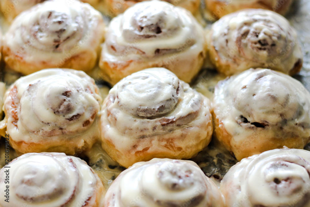 Tasty cinnamon buns rows with white cream-cheese sauce. Delicious ...