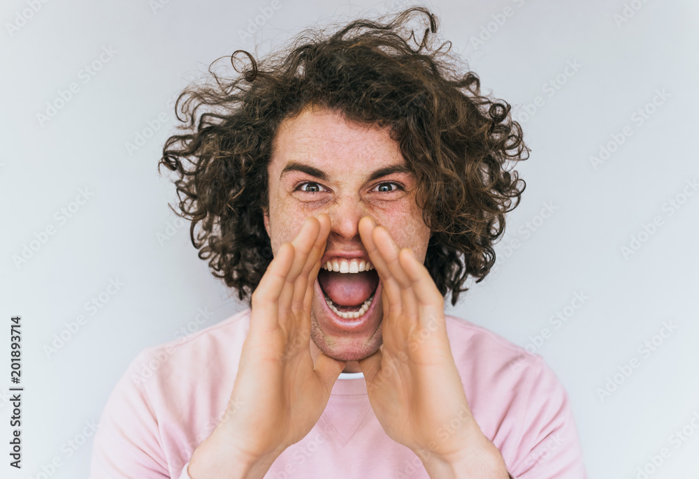 Horizontal shot of handsome angry male with curly hair opens mouth ...