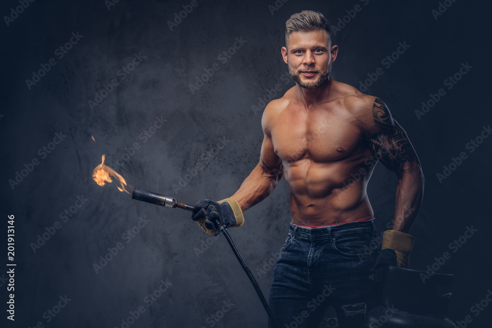 Brutal tattoed male welder with a stylish haircut and beard, with ...