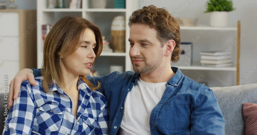 Close up of the young attractive man and woman sitting close on the ...