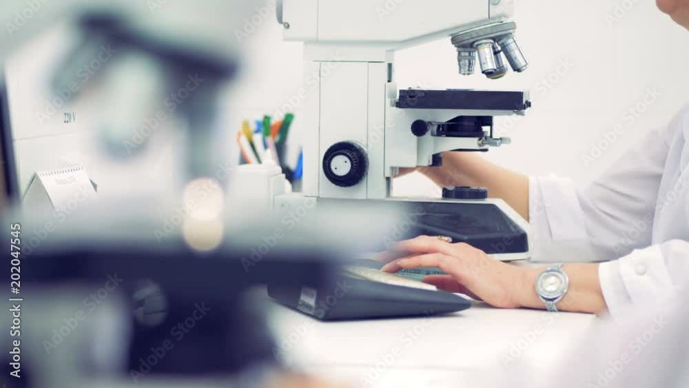 Female doctor uses microscope to examine a sample. 4K. Stock Video ...